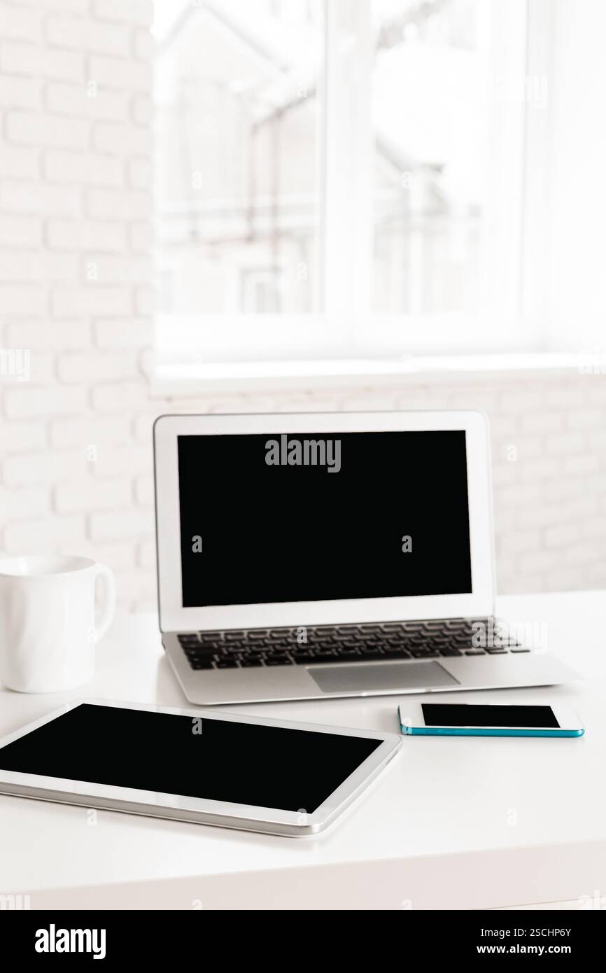Workstation with devices on a minimal desk beside a window during ...
