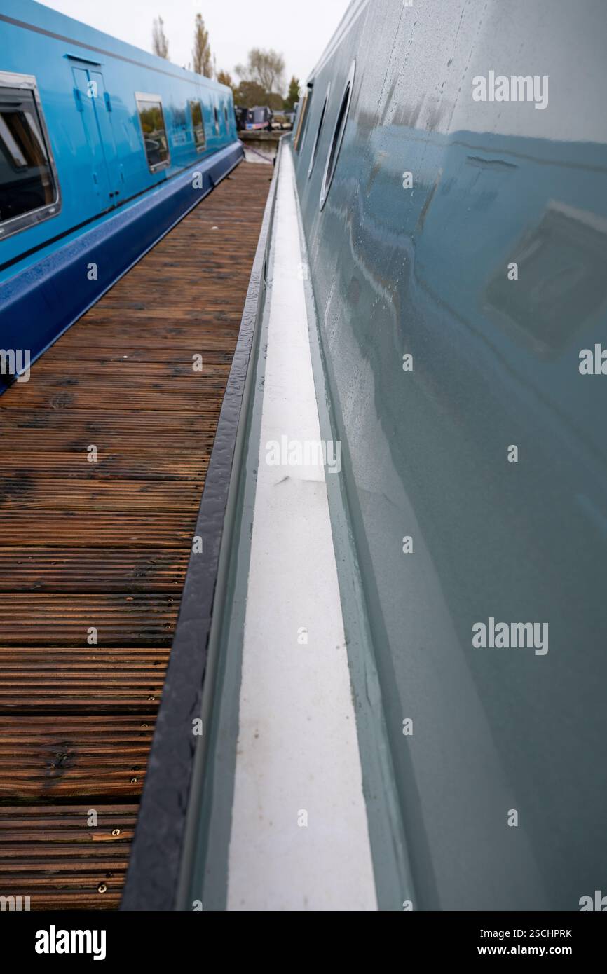 Close-up view along the gunwale of two canal boats moored side by side ...