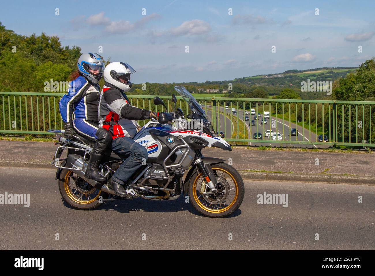 BMW R 1250 motorcycle riding two up crossing motorway bridge in Greater ...