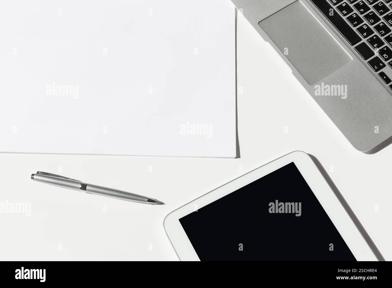 Workspace with laptop, notepad, tablet, and pen arranged on a clean ...