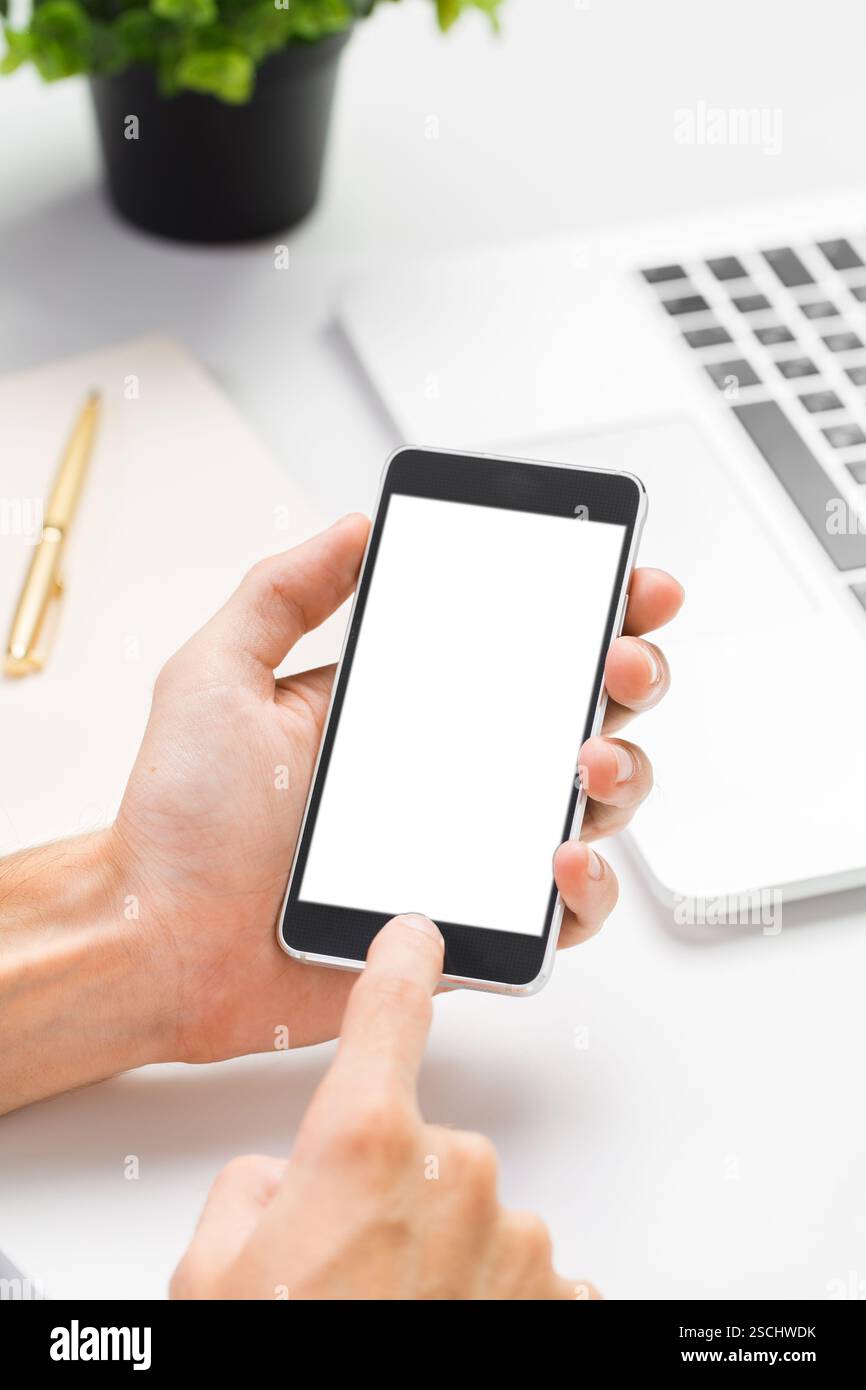 Hand holding smartphone with blank screen in a modern workspace ...