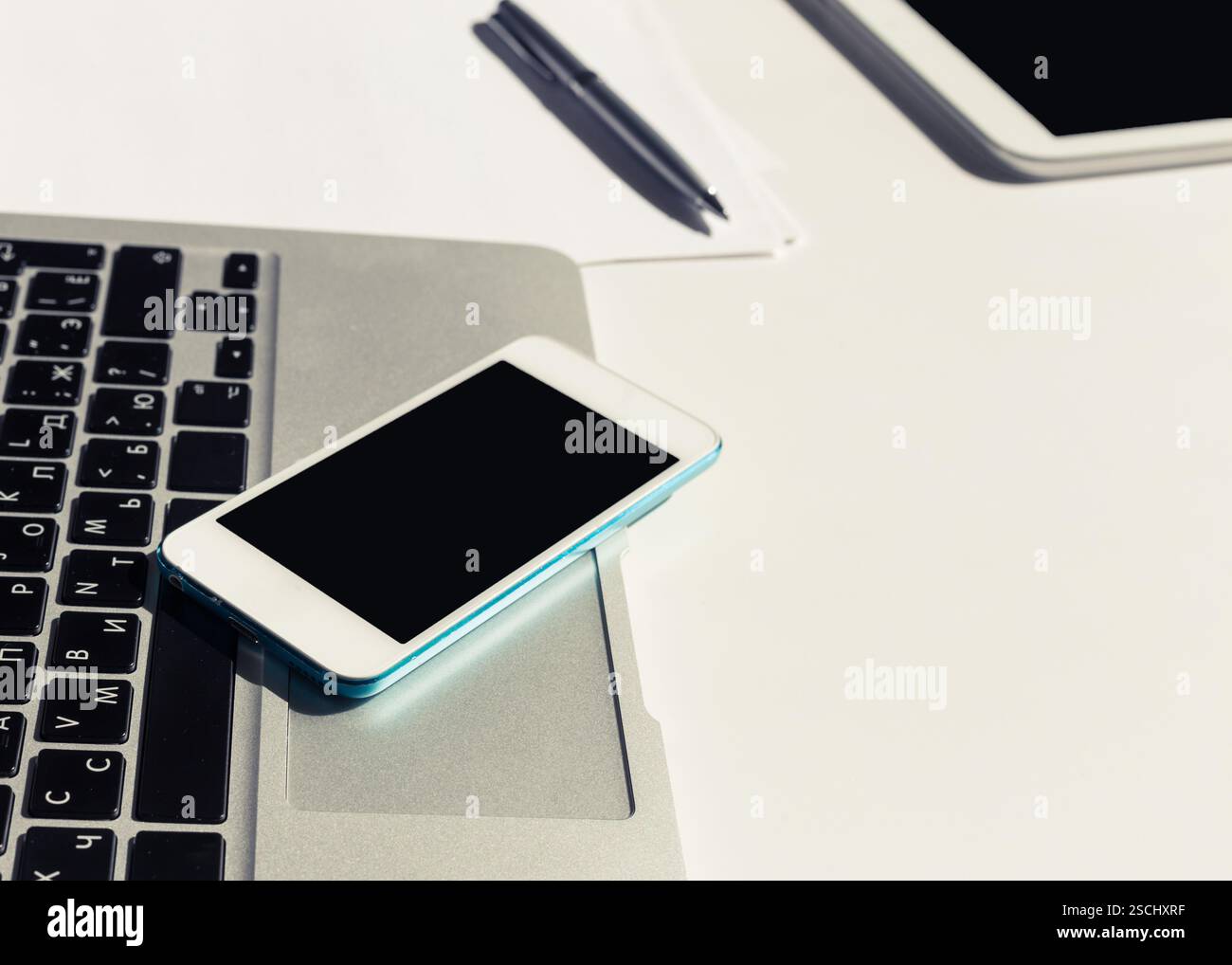 Technology setup on a desk featuring a laptop, smartphone, and tablet ...