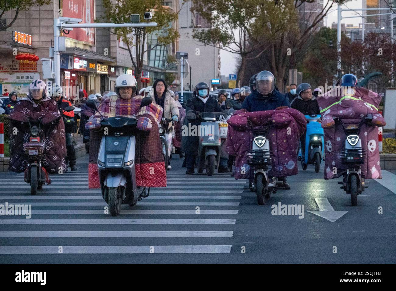 HAIAN, CHINA - FEBRUARY 7, 2025 - Citizens riding with thick clothes in ...