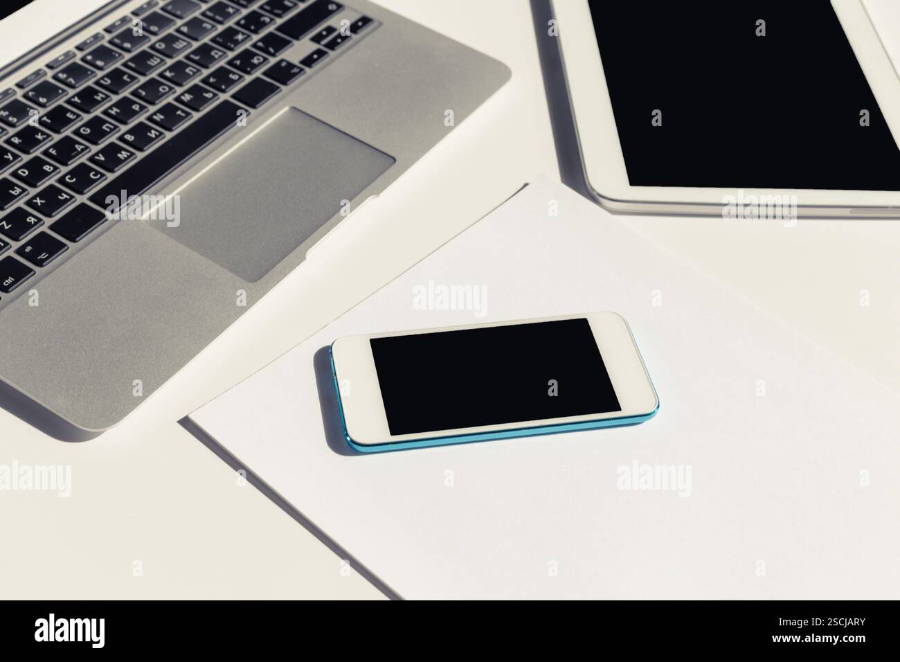 Workspace setup with laptop, tablet, and smartphone on clean desk ...