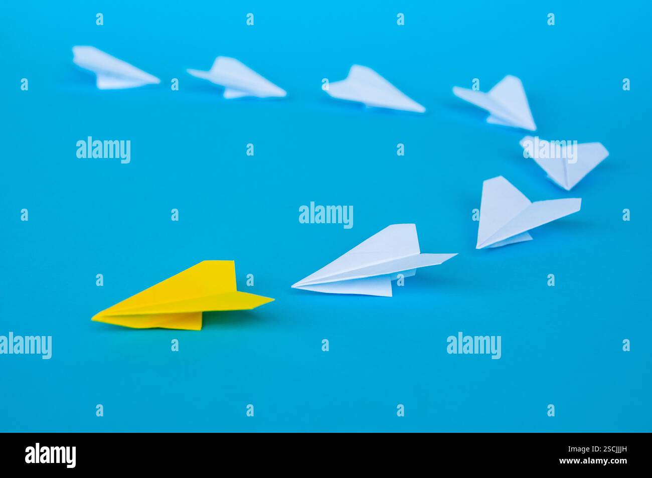 Side view of yellow paper airplane origami leading other white ...