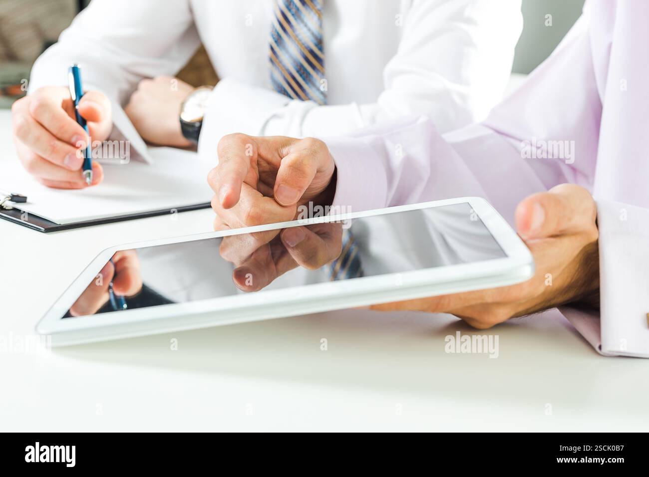 Professionals collaborate on project details using a tablet while ...