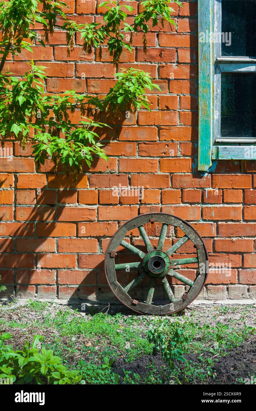 old wagon wheel against a brick wall Stock Photo - Alamy