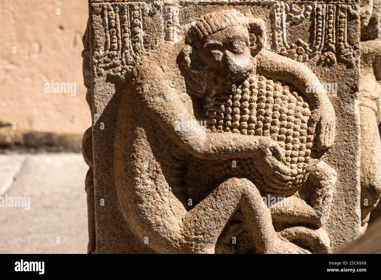 Ancient carving of a monkey holding a jackfruit on a pillar of an old ...
