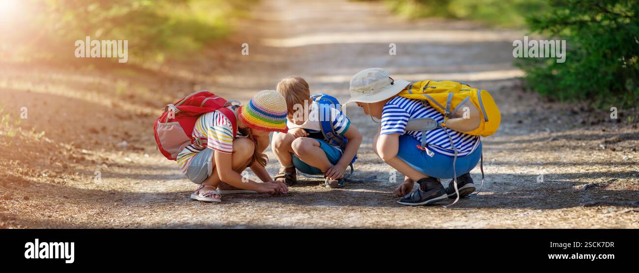 Three children sitting on the path and exploring something on it in a ...