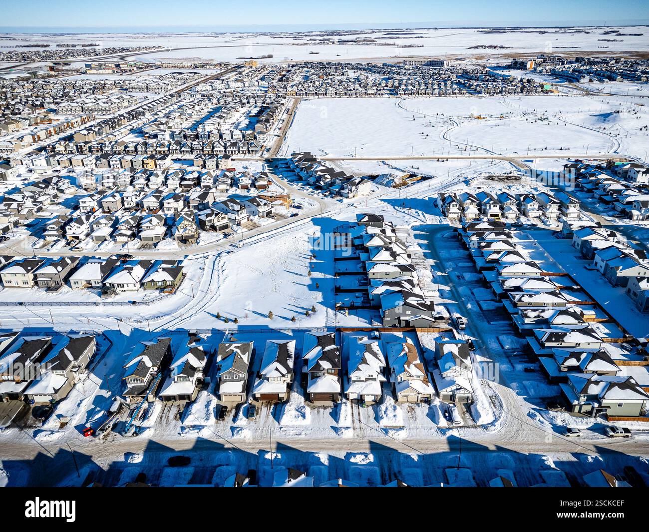 Snowy suburban neighborhood with houses and a few cars. The houses are ...
