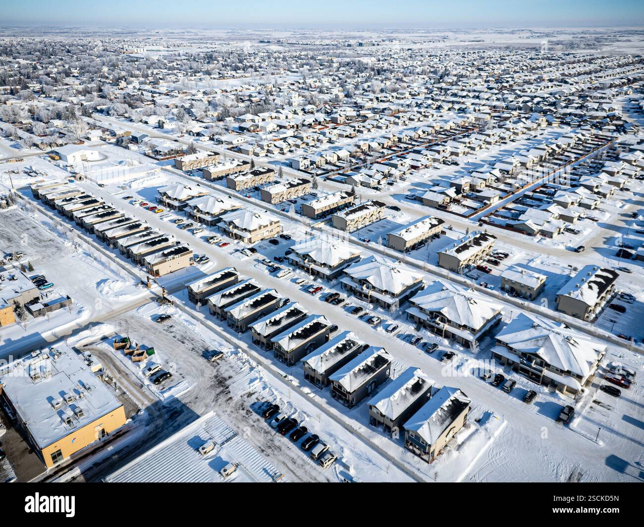 Snowy cityscape with many houses and cars. The houses are all covered ...