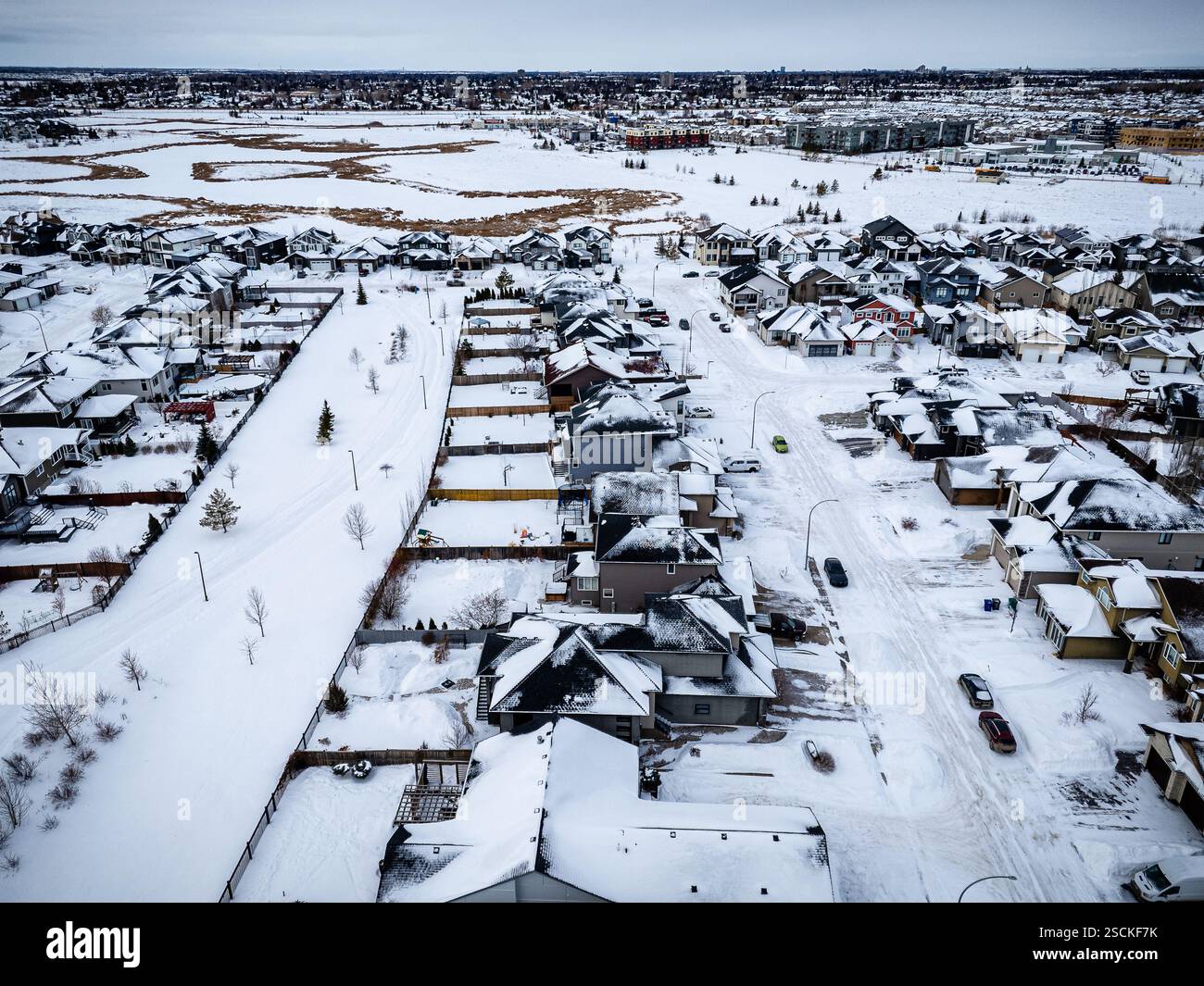 Snowy cityscape with houses and cars. The houses are mostly covered in ...