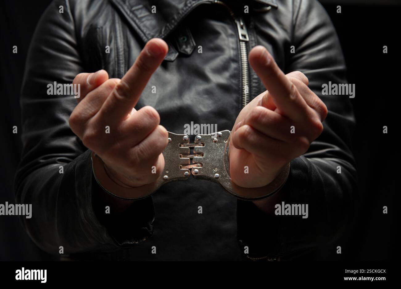 Hand in handcuffs with the middle finger extended, gesture of defiance ...