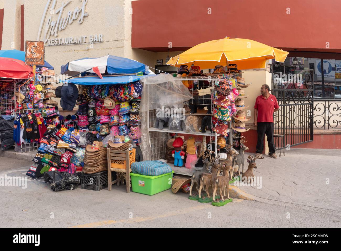Street vendor selling souvenirs on a stand leans against the wall of ...