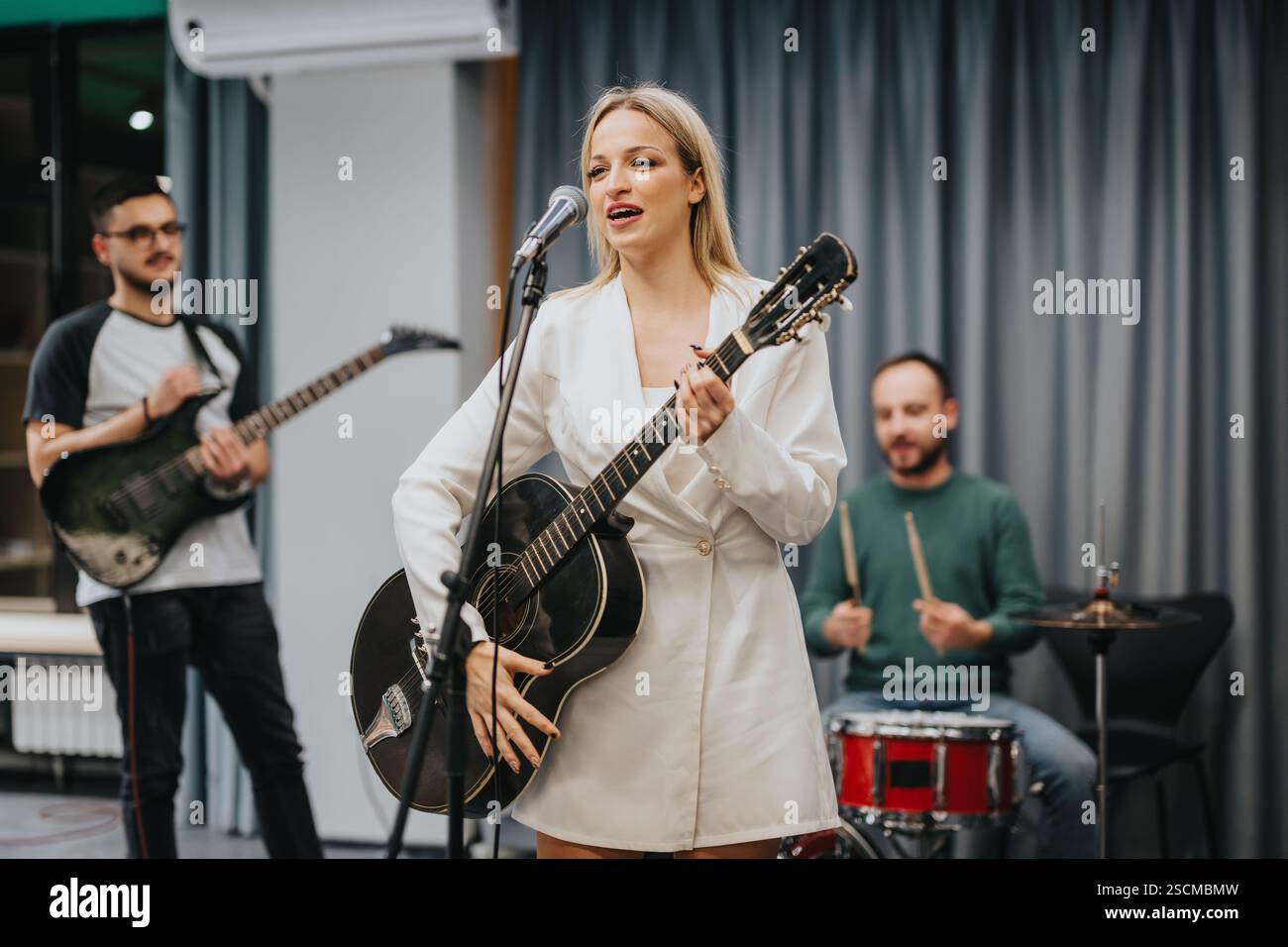 Musical group performing in a studio featuring guitars and drum set ...