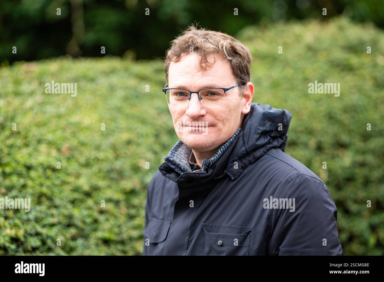 Portrait of a 45 yo white male wearing a dark winter jacket against a ...