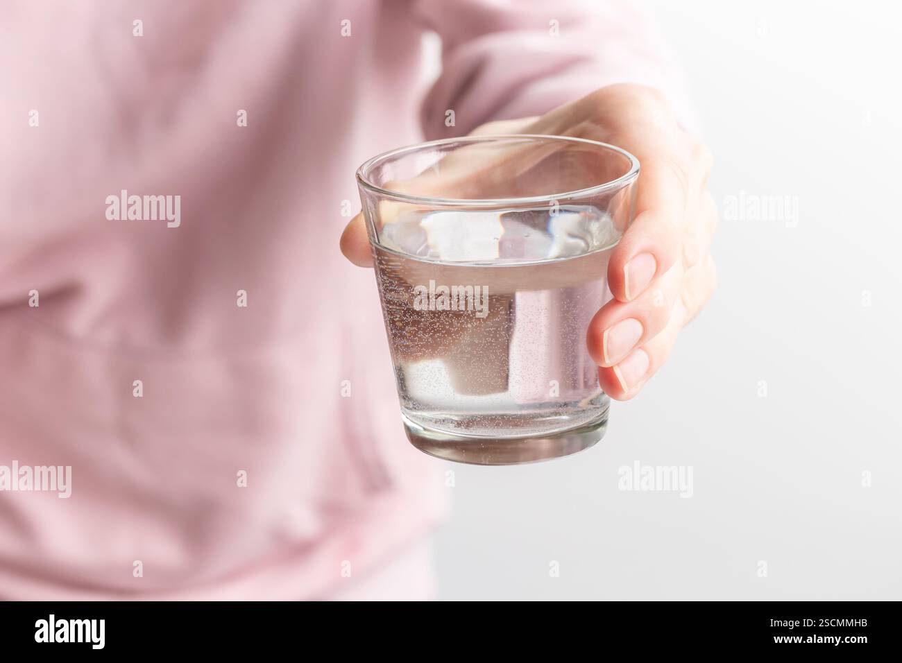 Female hand holding a clear glass of water. A glass of clean mineral water in hands, healthy ...