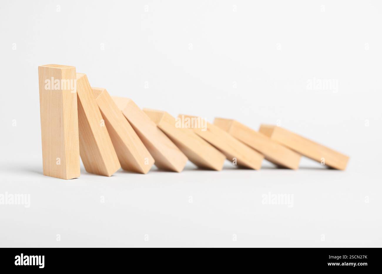 Domino effect. Wooden blocks falling on light background Stock Photo ...