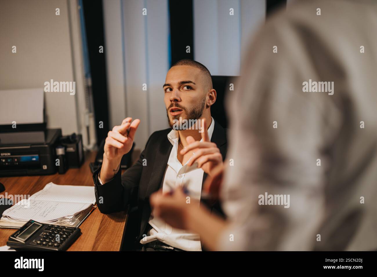 Business professional engaged in conversation at an office desk ...