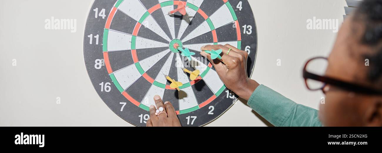 Close-up of person playing darts, aiming at target on dartboard. Hand ...