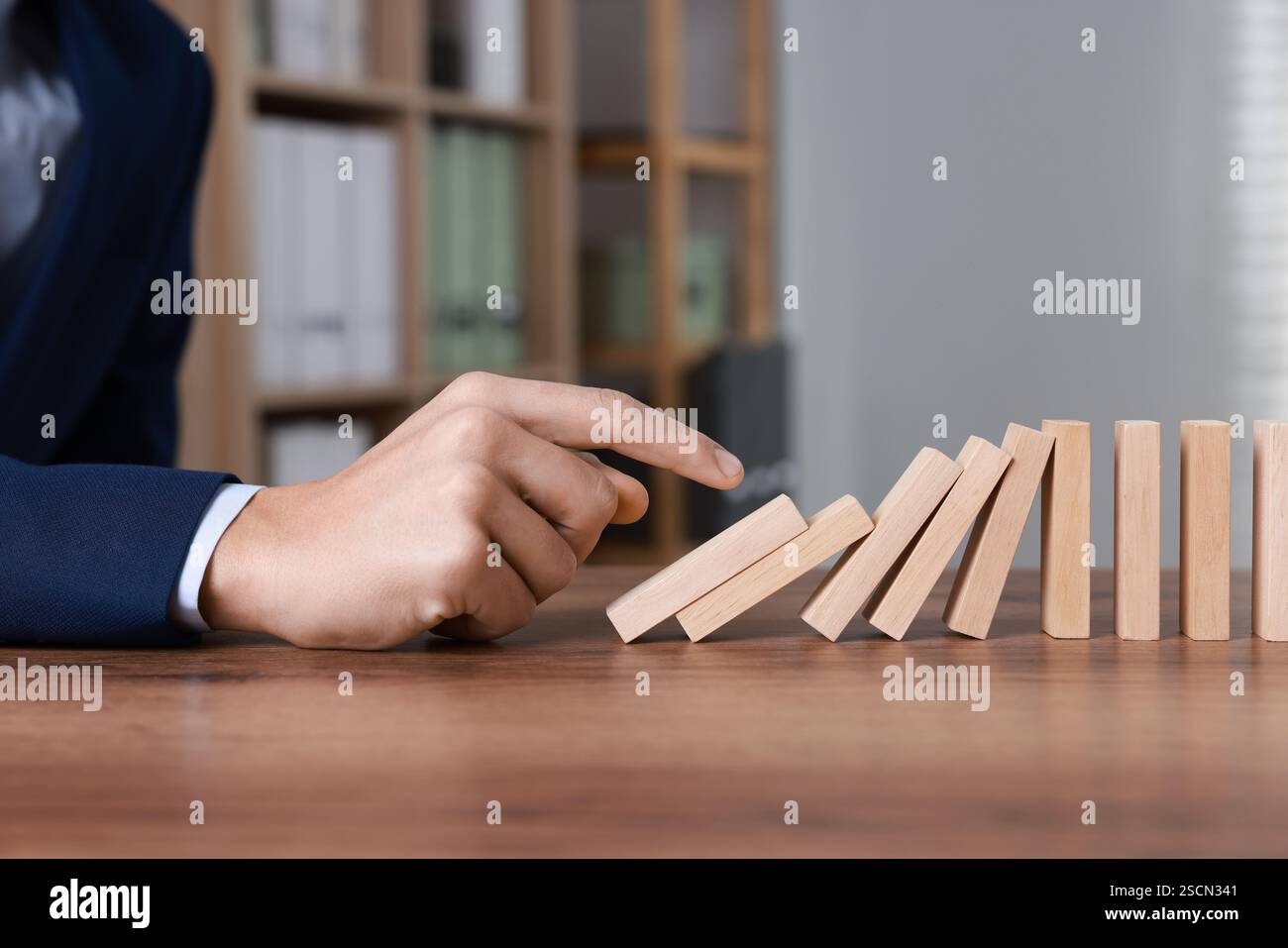 Domino effect. Man pushing wooden blocks at table, closeup Stock Photo ...