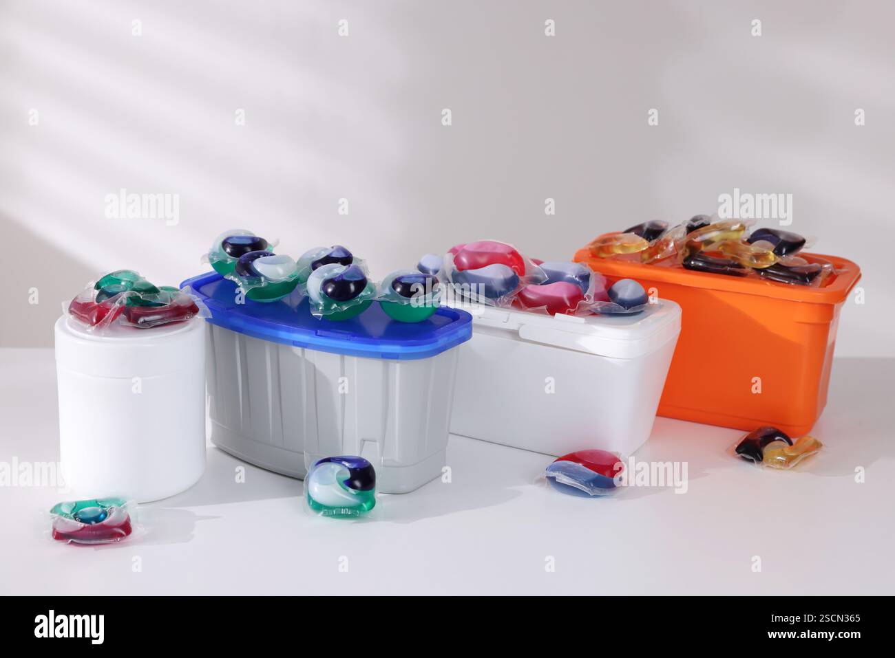 Containers with different laundry detergent capsules on white ...