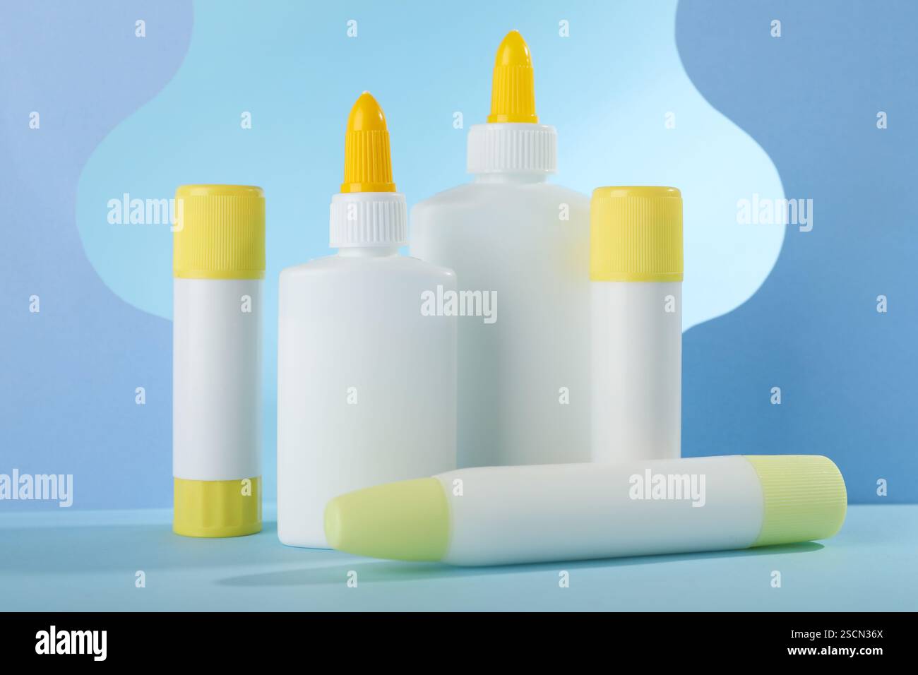 Different types of glue and paper cutouts on light blue background ...