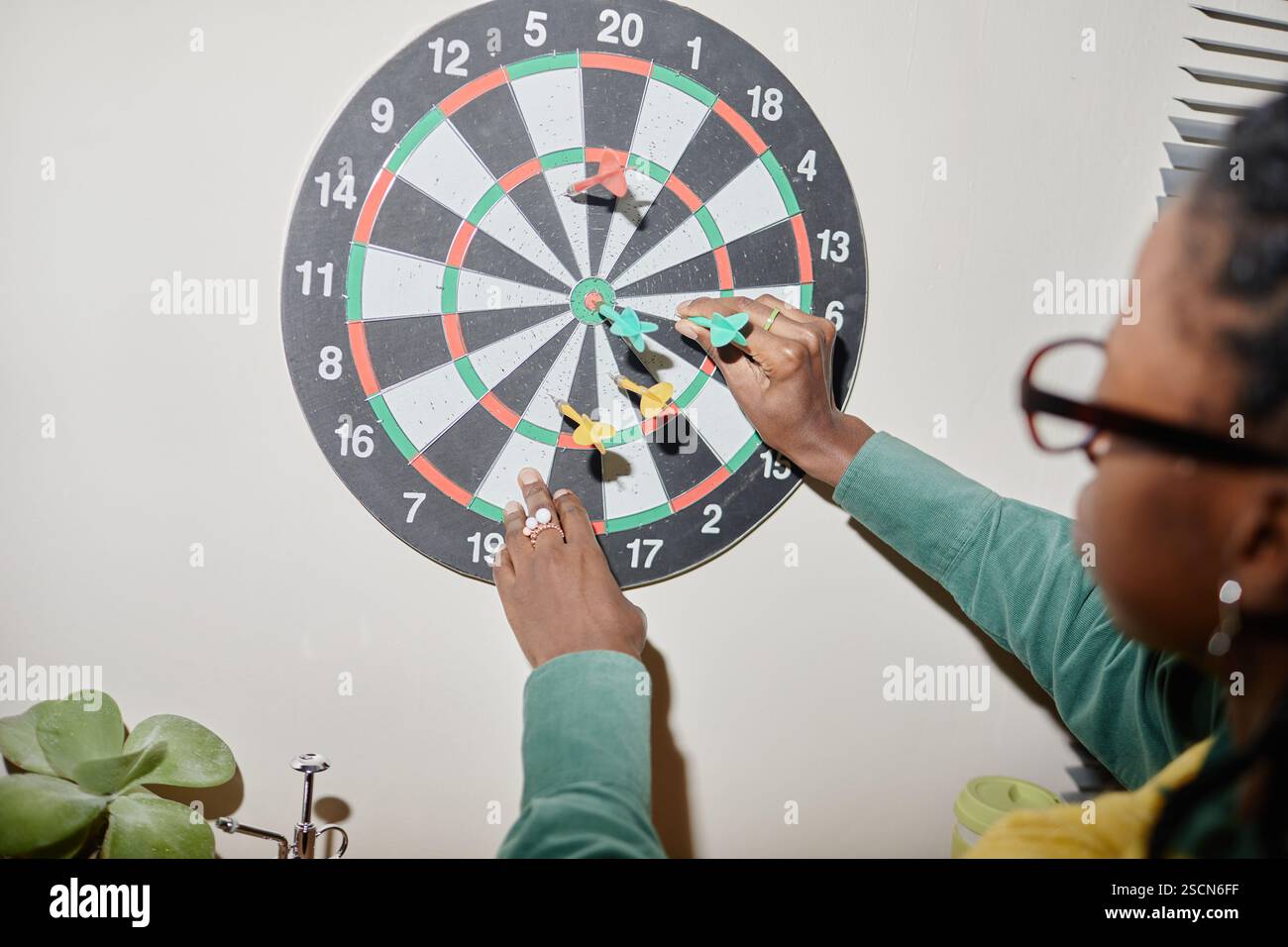 Individual adjusting darts on wall-mounted dartboard, fine-tuning ...