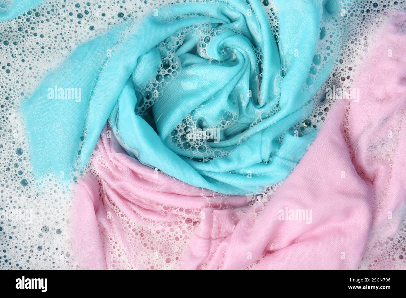 Colorful clothes soaked in water before washing, top view Stock Photo ...