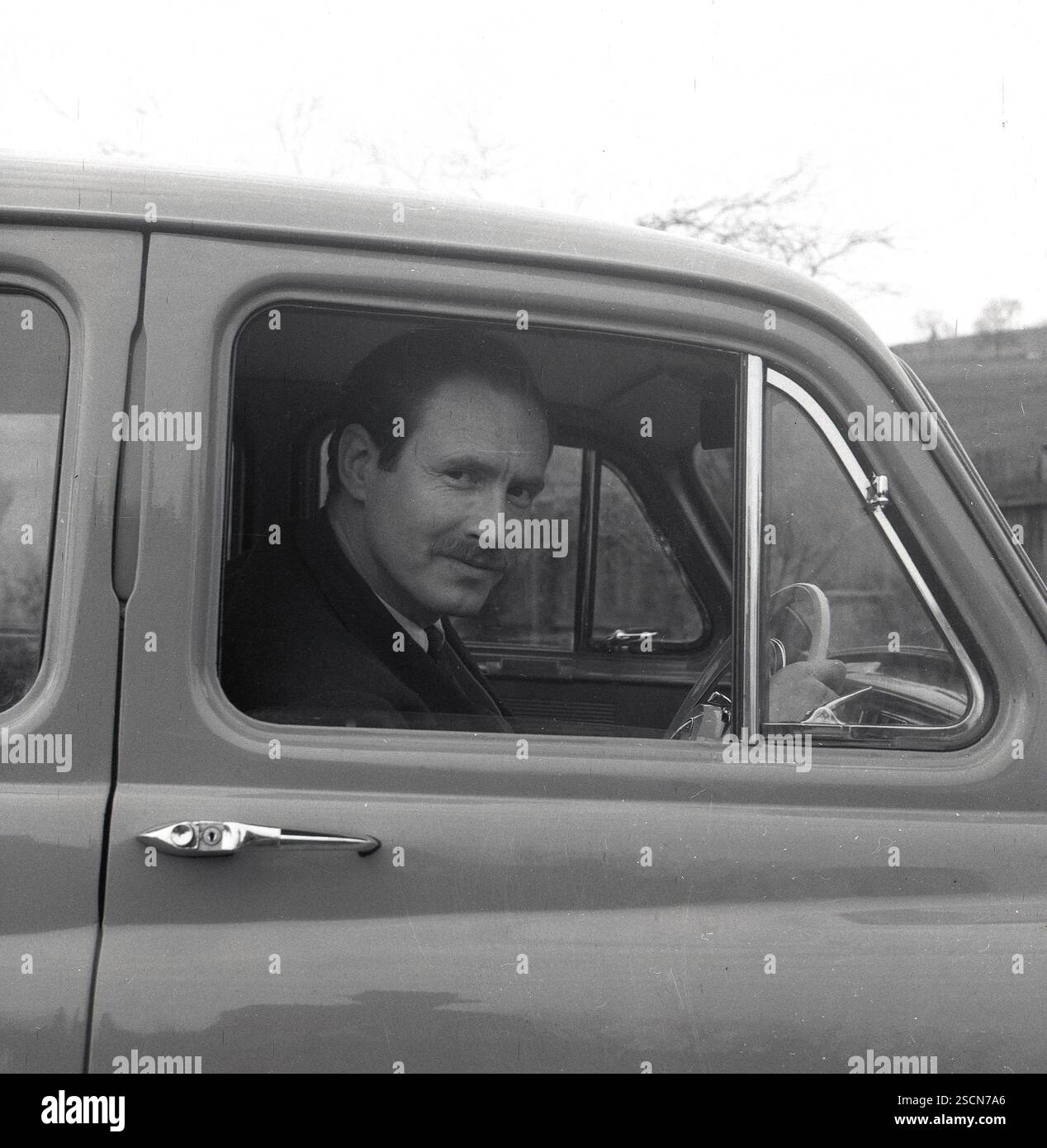 1950s, historical, Richard Irvine sitting in the driver's seat, hands ...