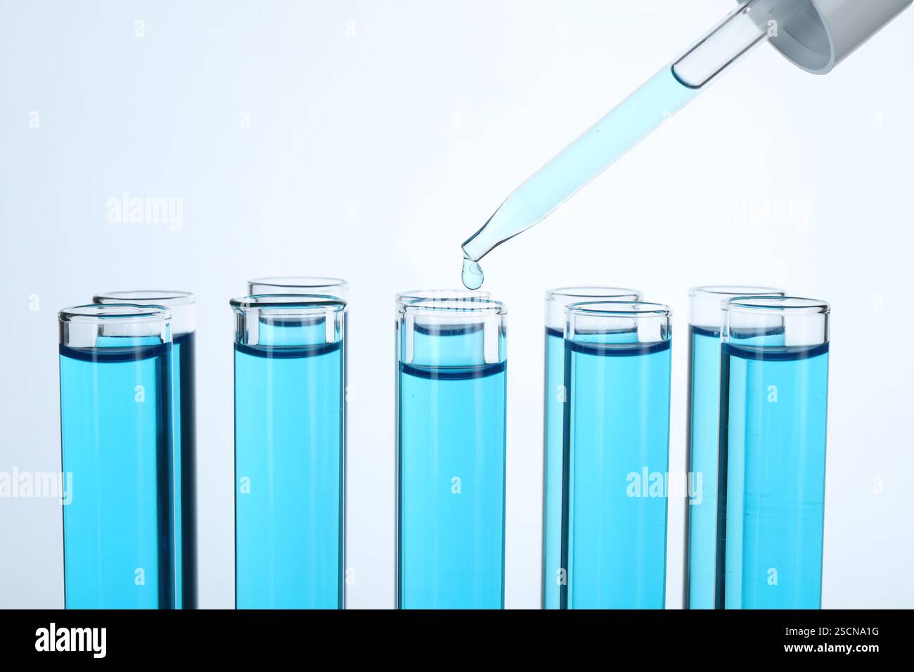 Dripping liquid into test tubes on white background Stock Photo - Alamy