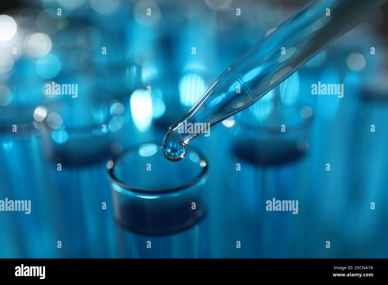 Dripping liquid into test tubes on blurred background, closeup Stock ...