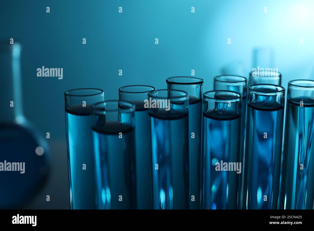 Test tubes with liquid on blue background, closeup. Color toned effect ...