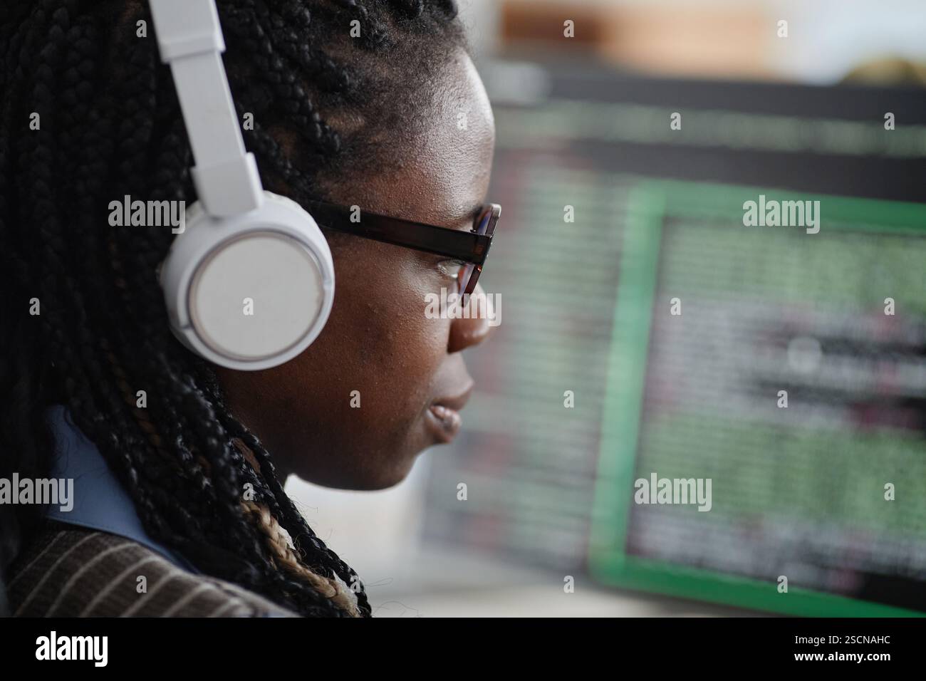 Focused African American person wearing headphones and coding on ...