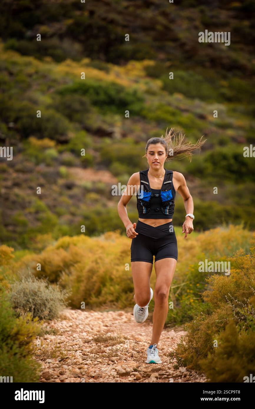 Female trail runner wearing black sportswear and a hydration vest ...