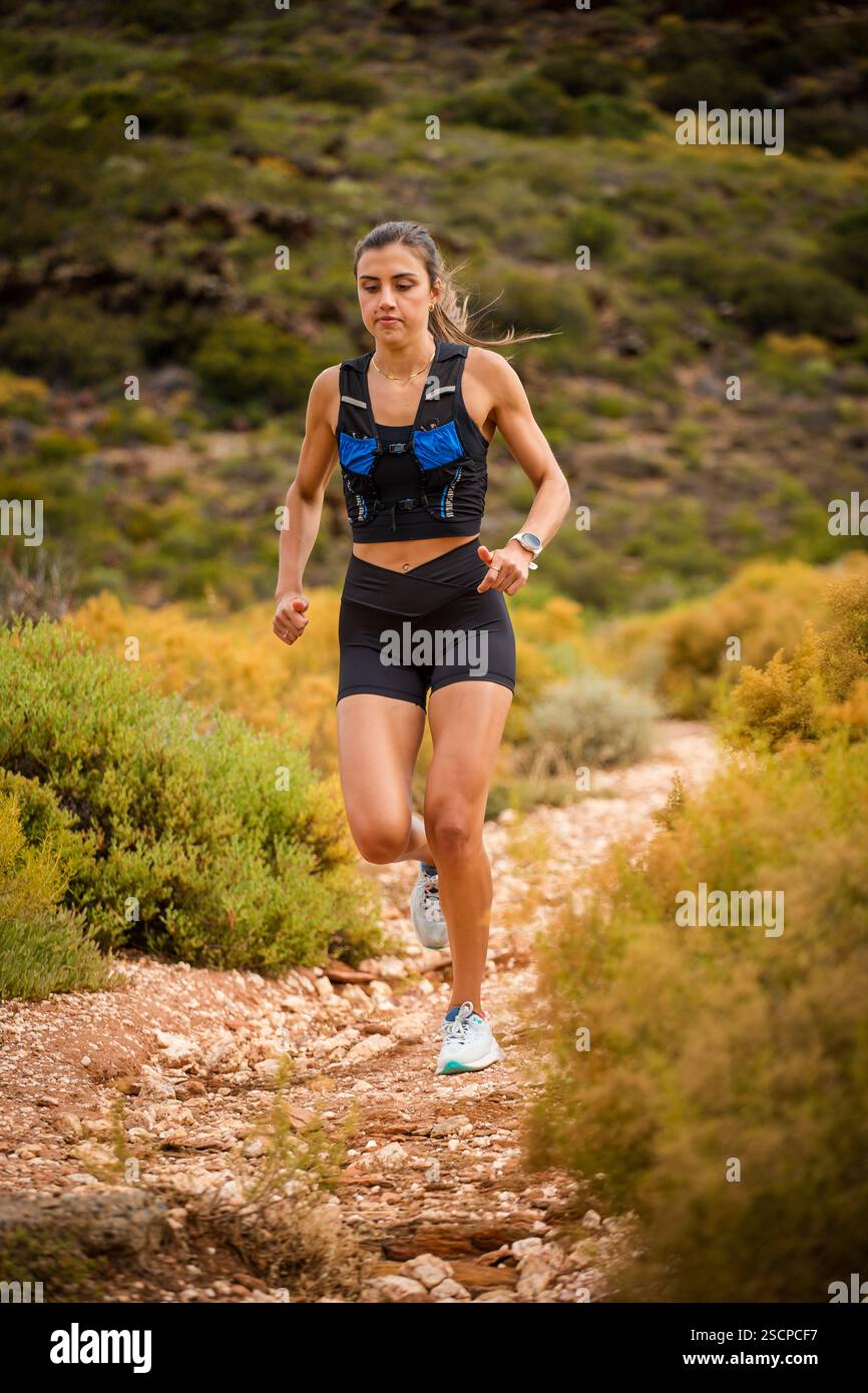 Female trail runner wearing black sportswear and a hydration vest ...