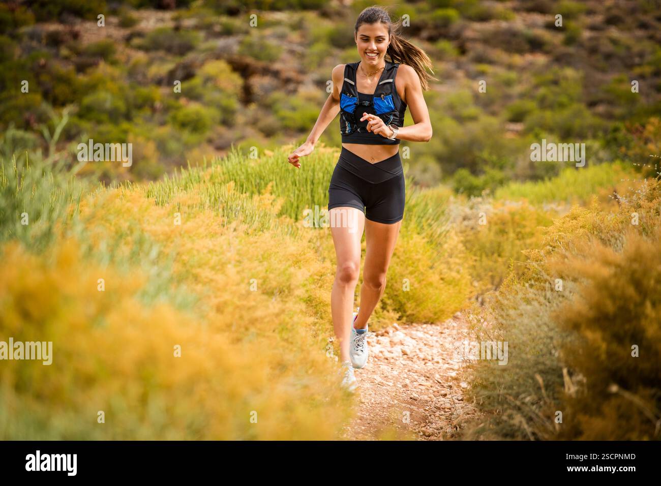 Female trail runner wearing black sportswear and a hydration vest ...