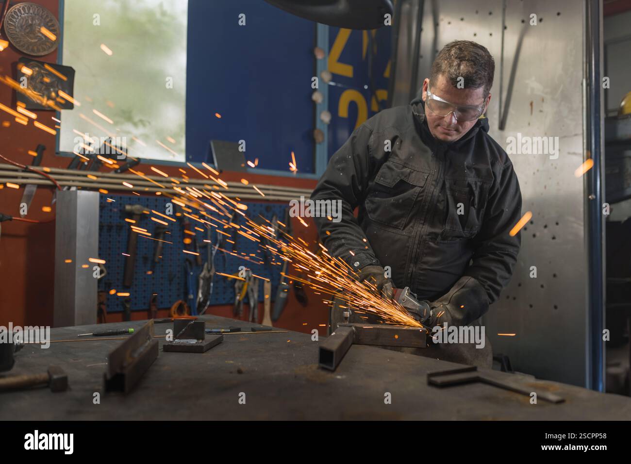 Male welder handling portable professional angle grinder to grind metal ...