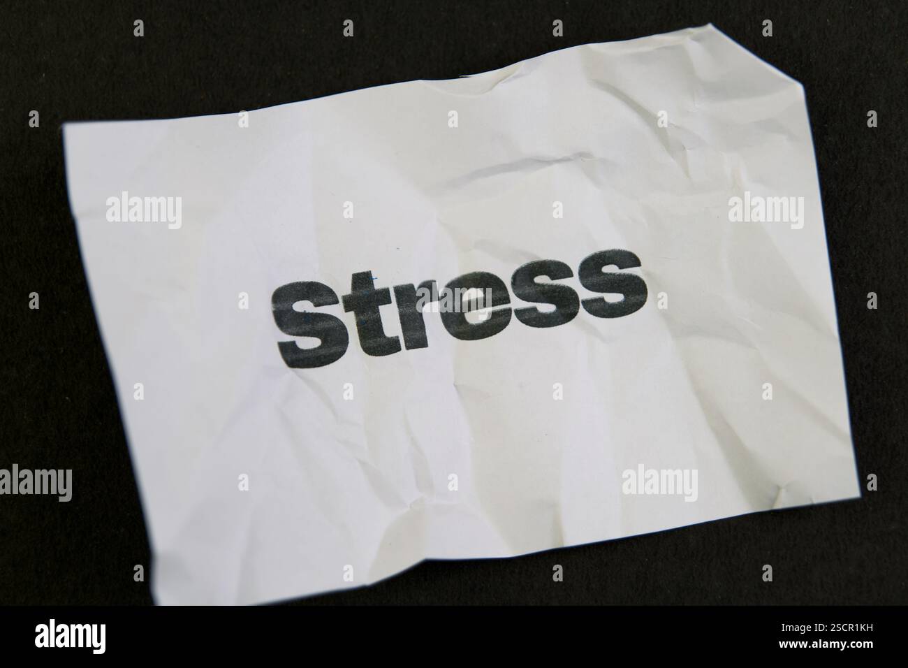 A crumpled piece of paper displays the word stress, symbolizing ...