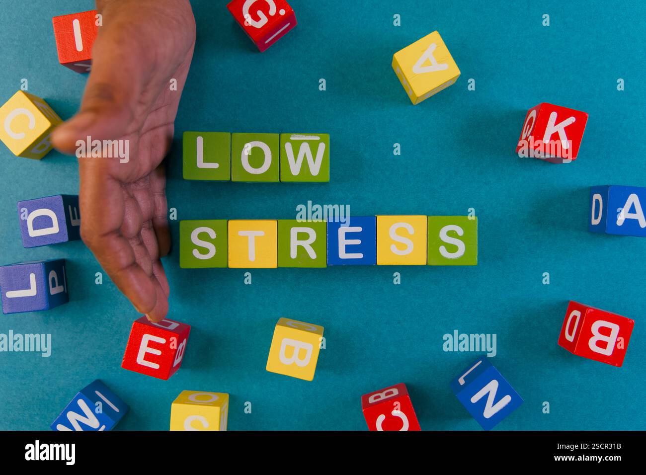 Hand arranging colorful blocks to form the words low stress, promoting ...