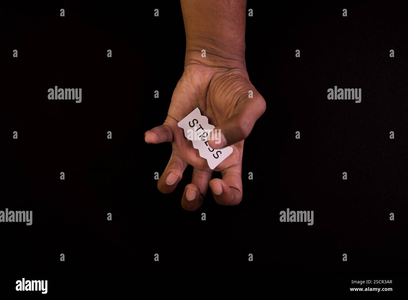 A person's hand holds a label reading stress against a black backdrop ...