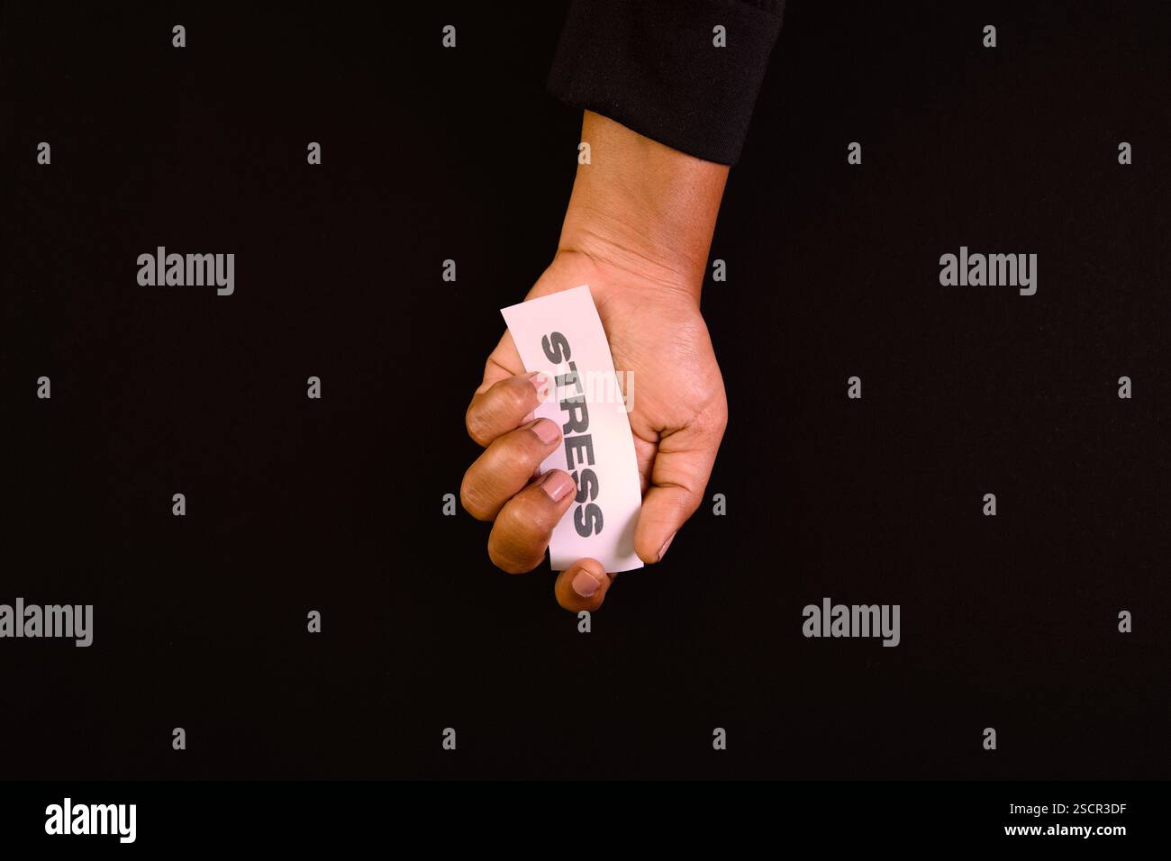 A hand tightly grips a piece of paper labeled stress, symbolizing ...