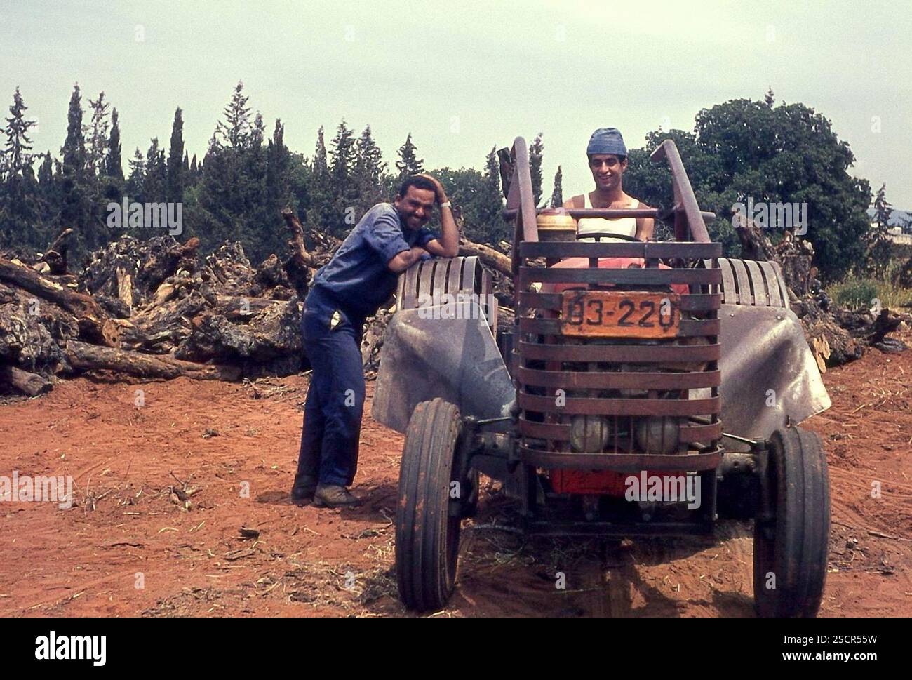Two lumberjacks at work. One is driving a tractor, the other is smiling ...