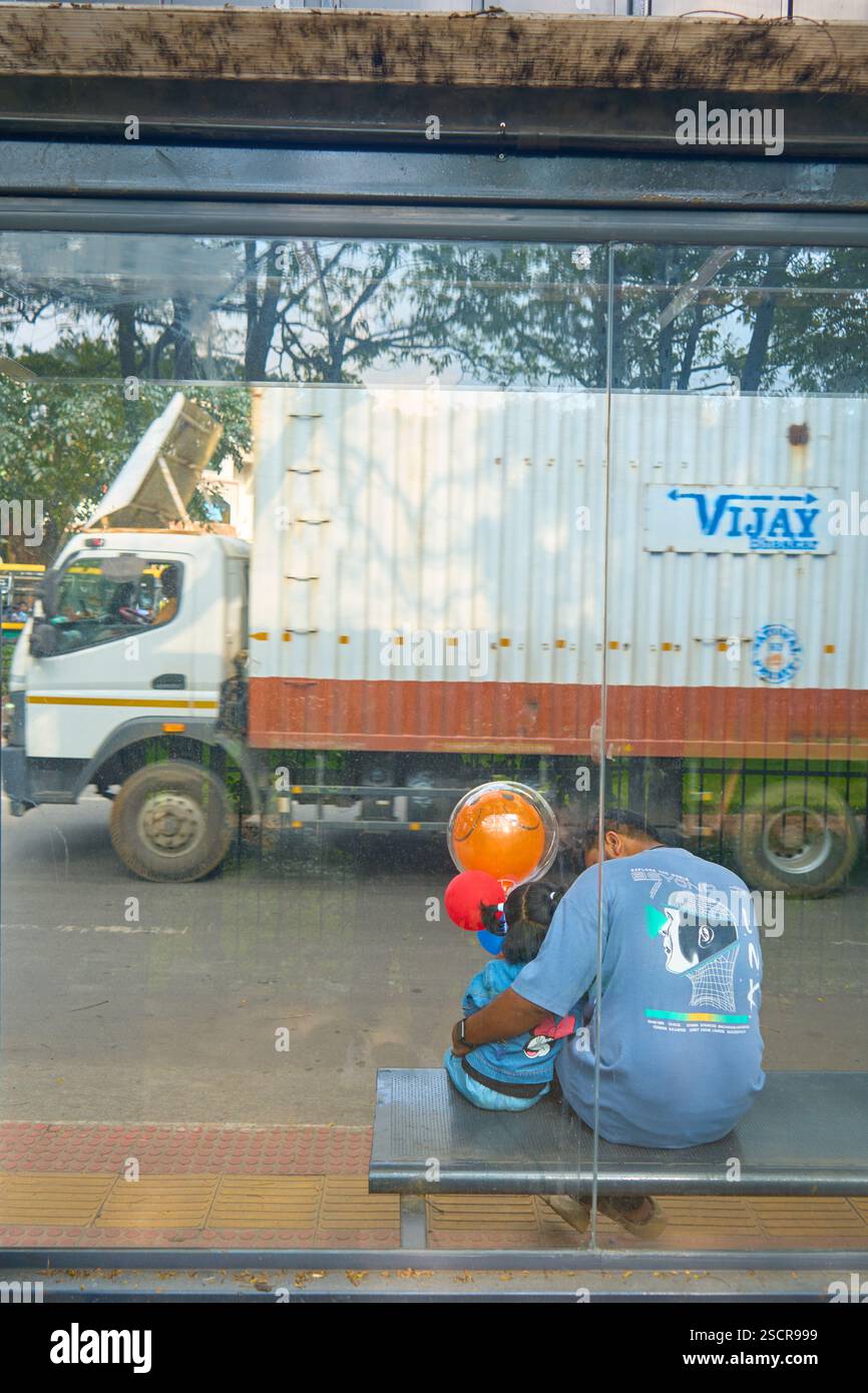 A father and child share a quiet moment at a bus stop, holding colorful ...