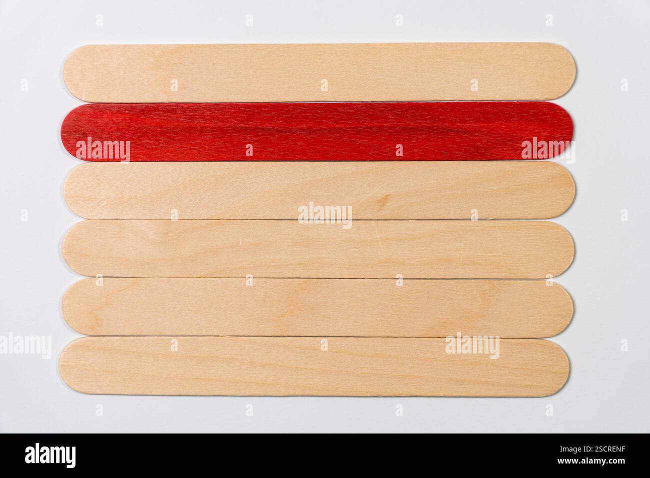 Stack of Wooden Sticks with One Red Stick in the Center Stock Photo - Alamy