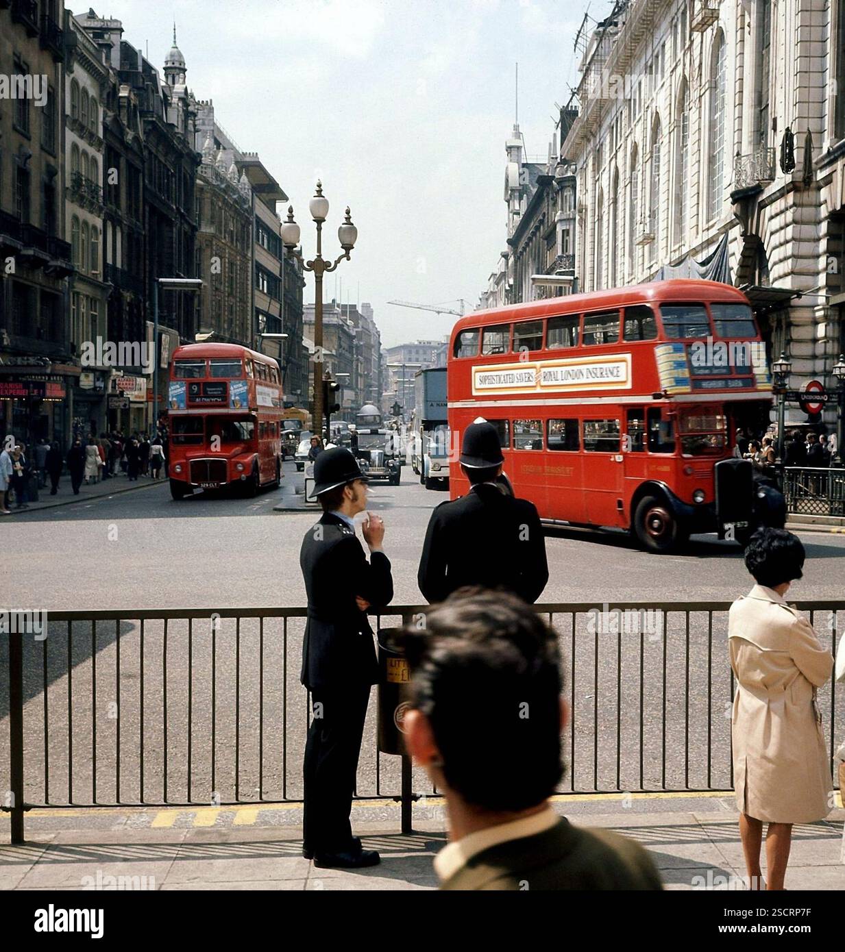 Double-decker buses and two police officers in the foreground in London ...