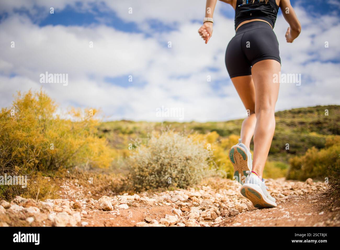 Female trail runner wearing black sportswear and a hydration vest ...