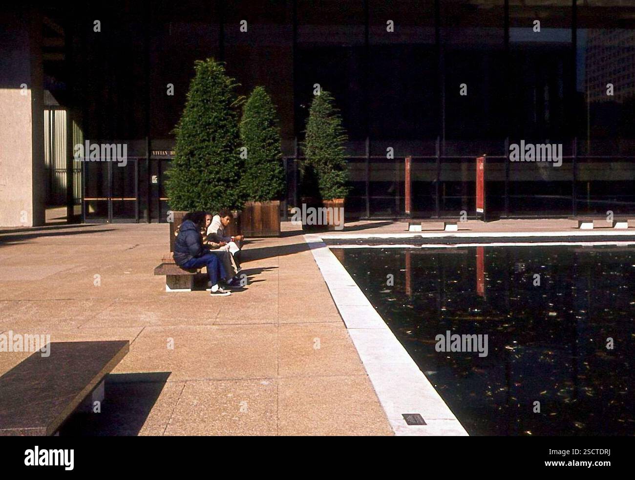People on a bench in a square at Lincoln Center in New York. [automated ...