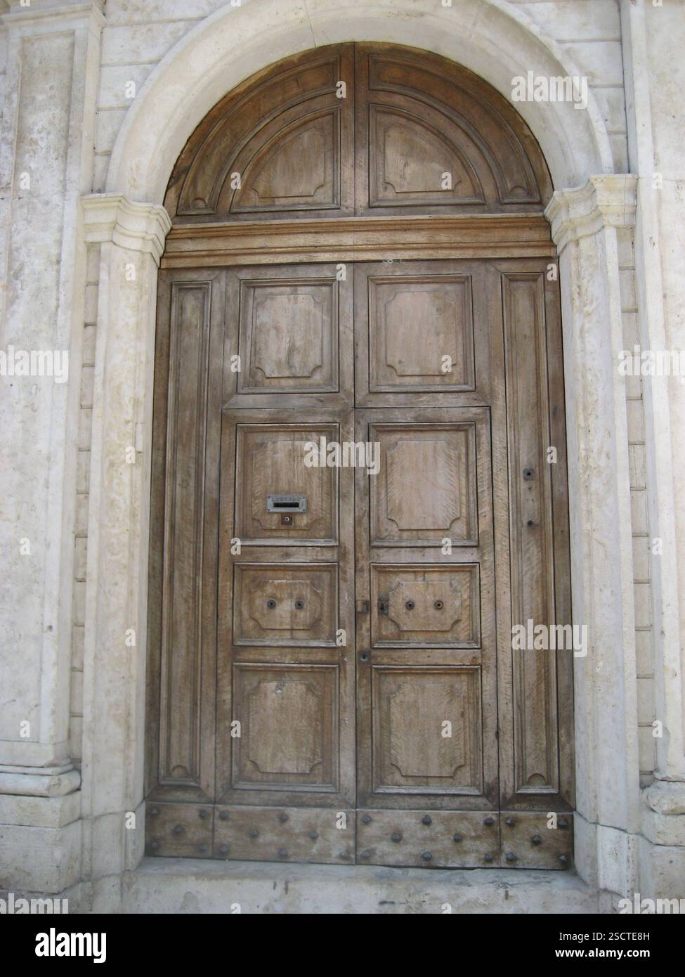 An ancient arched wooden door on an old historic building in Assisi ...