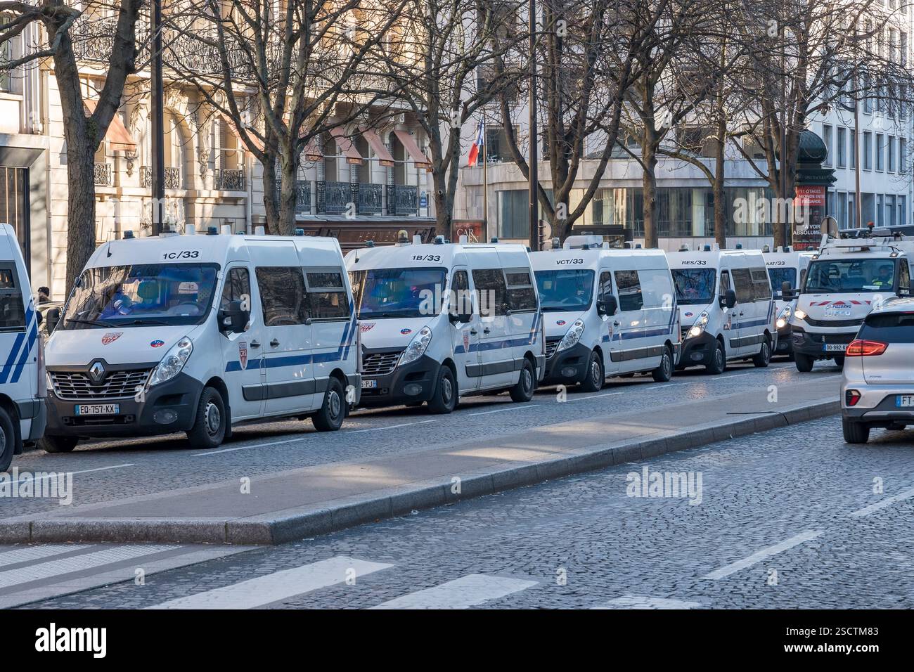 Police vans lined up along a busy street in an urban setting during ...